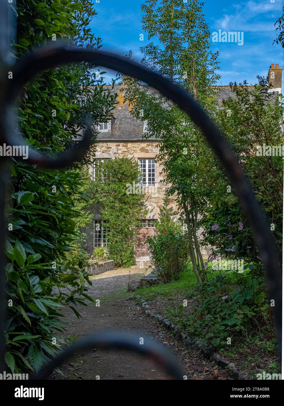 The facade of a manor house seen through a iron gate. Taken on a summer ...