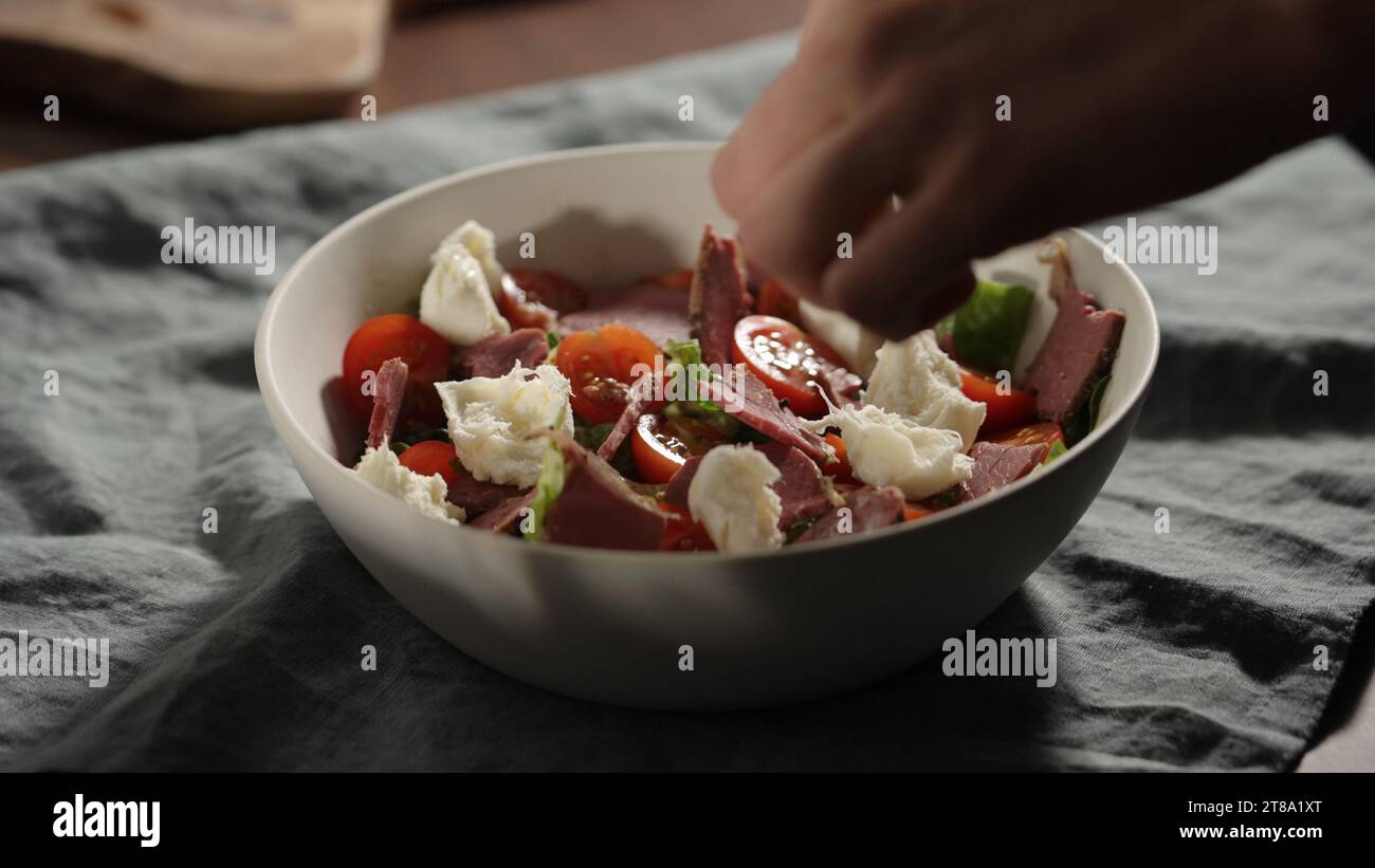 man add mozzarella, making salad in white bowl, wide photo Stock Photo ...
