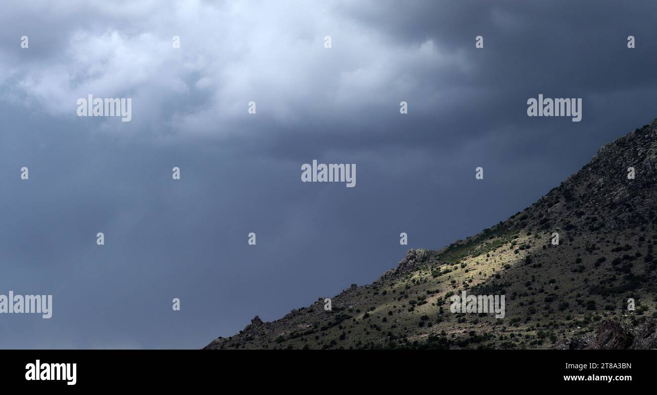 light and shadow falling from dramatic sky onto mountainside Stock ...
