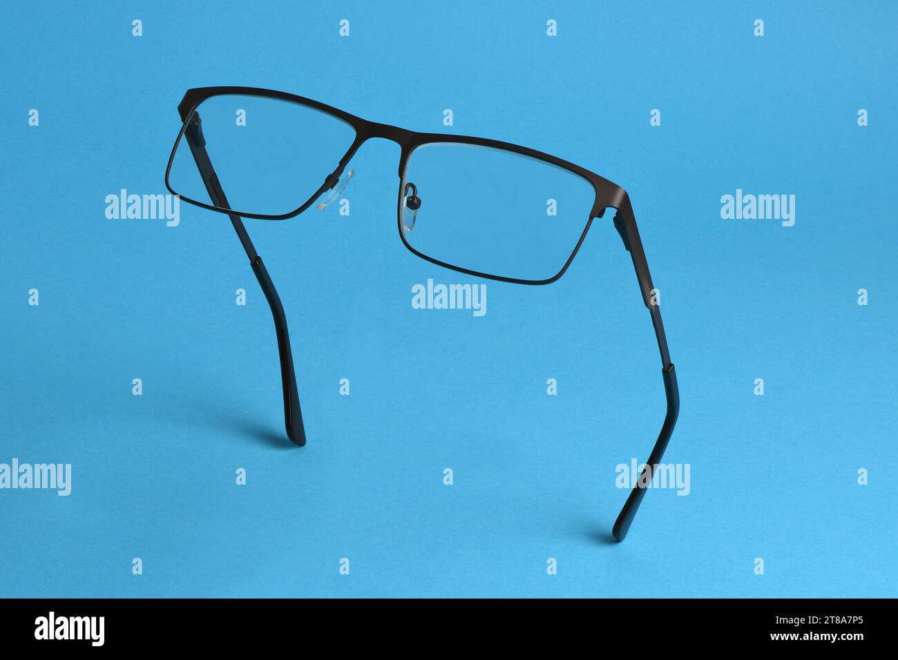 Reading glasses isolated on blue background. Glasses hang in air. High ...