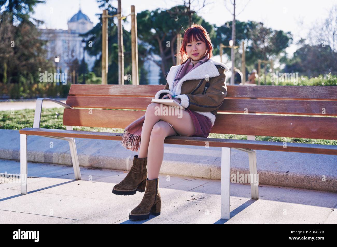 real teenager sitting on a park bench with a notebook in her hand Stock ...
