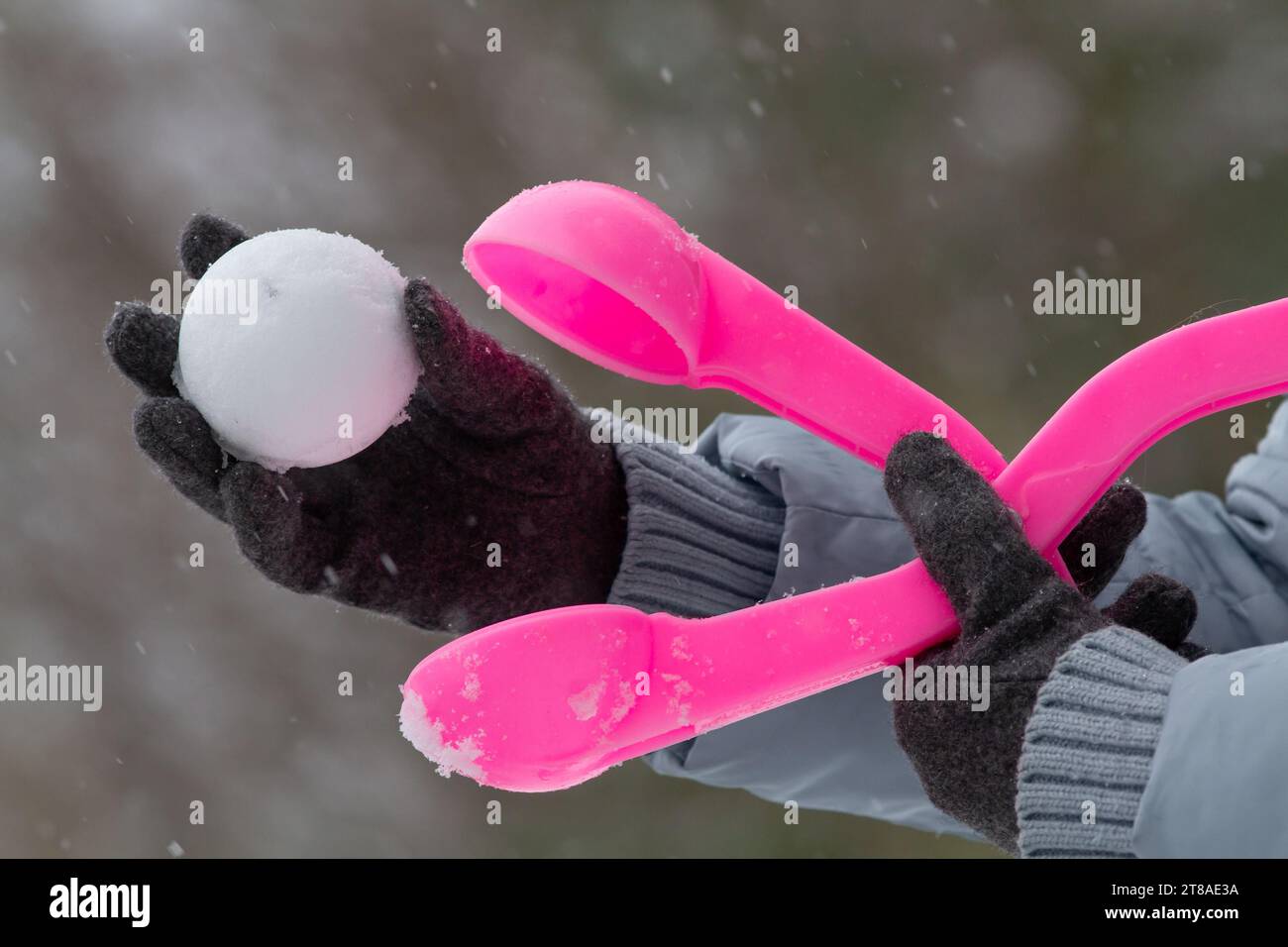 a woman's hands, wearing gloves, take out a round snowball from a form ...