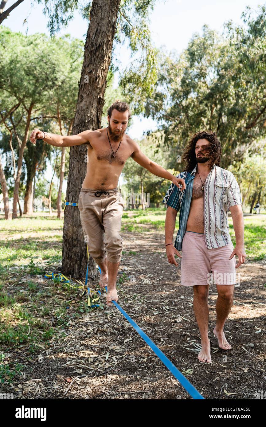 Two men slacklining in city park during summer day Stock Photo - Alamy