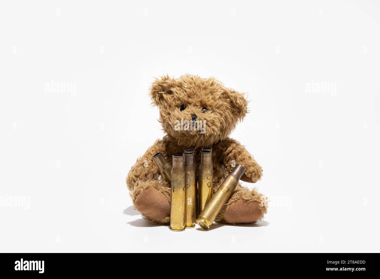 Empty machine gun cartridges and a brown teddy bear on a white ...