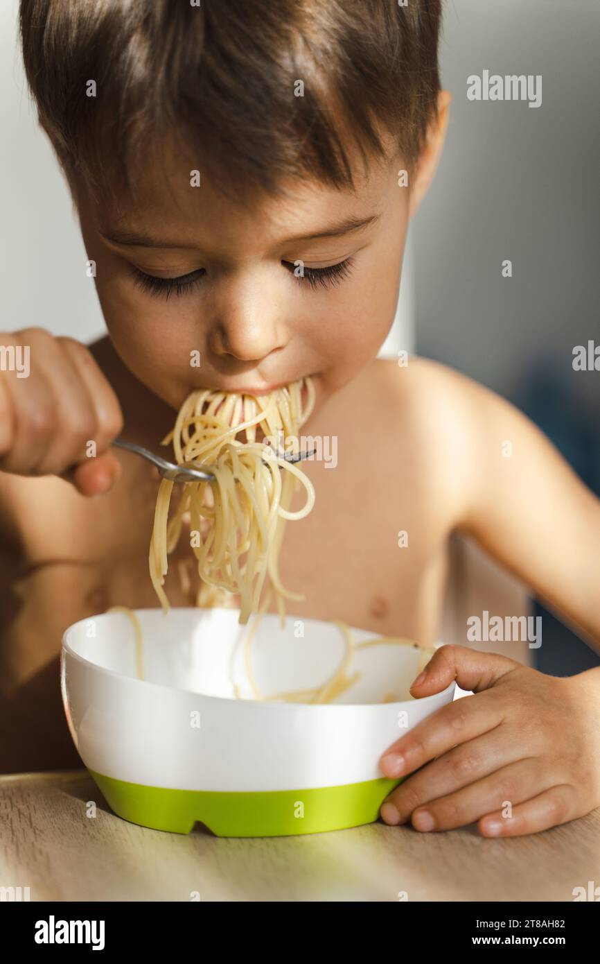 Cute toddler boy eating his favorite food - Spaghetti Stock Photo - Alamy