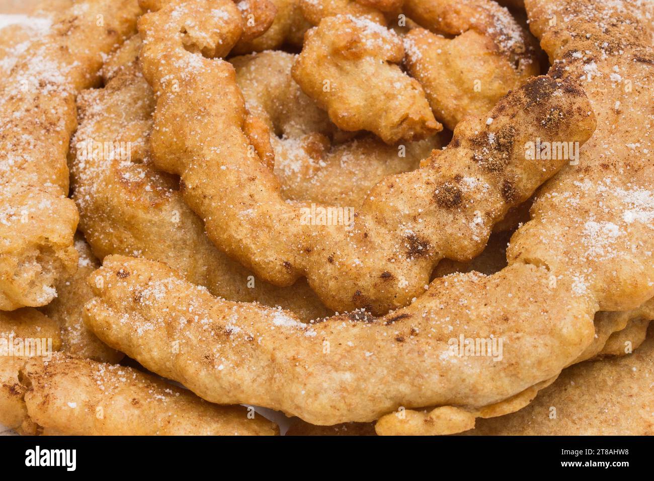 A close-up of a Spanish funnel cake covered with powdered sweetener and ...