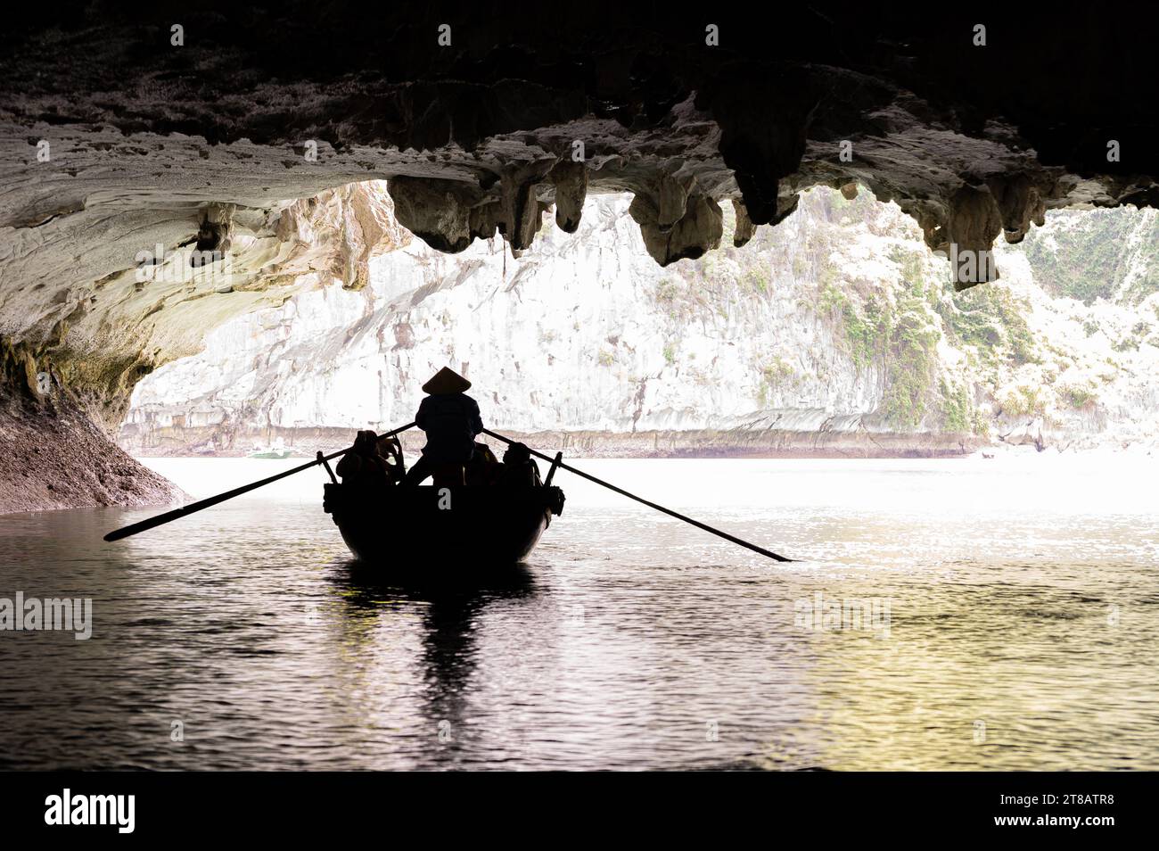 Sihouette of a rowing boat in the dark caves of Halong Bay, Vietnam ...
