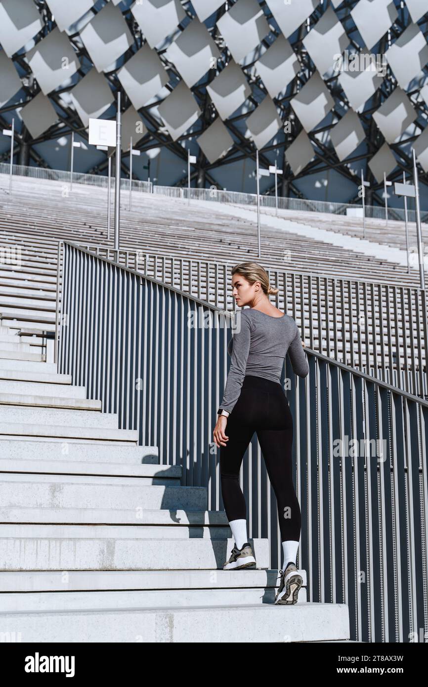 Woman athlete wearing female sportswear climbing stairs of outdoor ...