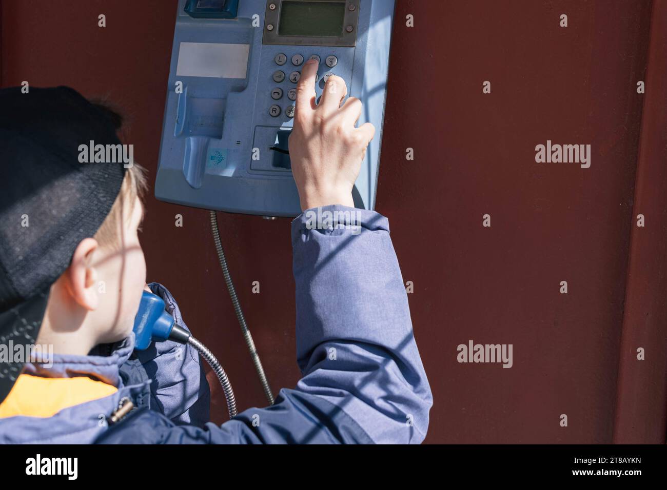 a boy of European appearance in a telephone booth is talking on the ...
