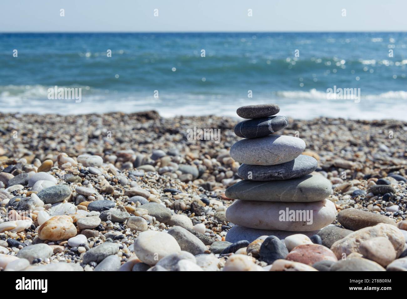 Pyramid of sea pebbles on a sunny sandy beach. The concept of life ...