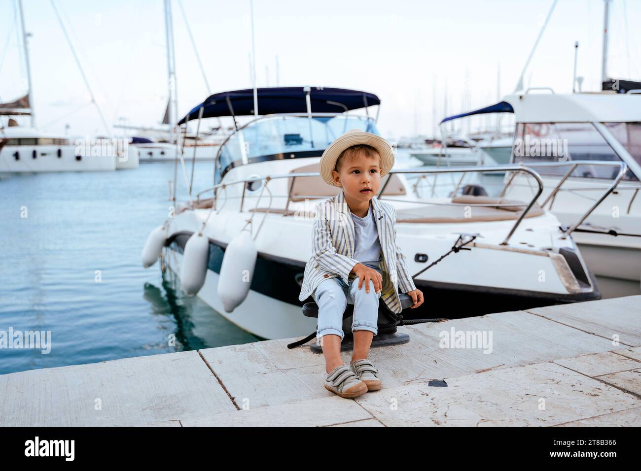 Cute stylish boy sitting on the pier near yacht in marina Stock Photo ...