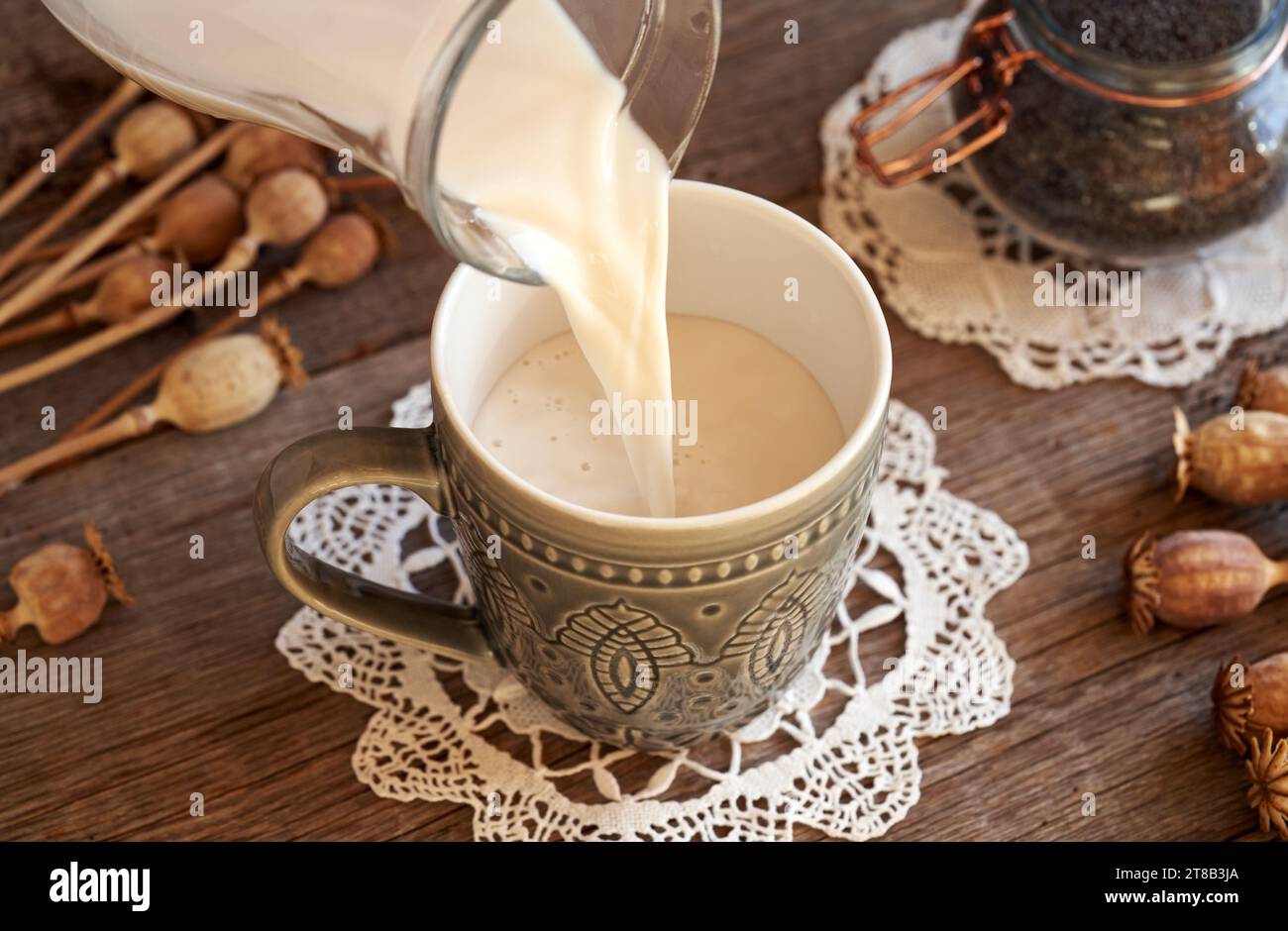 Homemade vegan poppy seed milk being poured from a glass jug into a cup ...