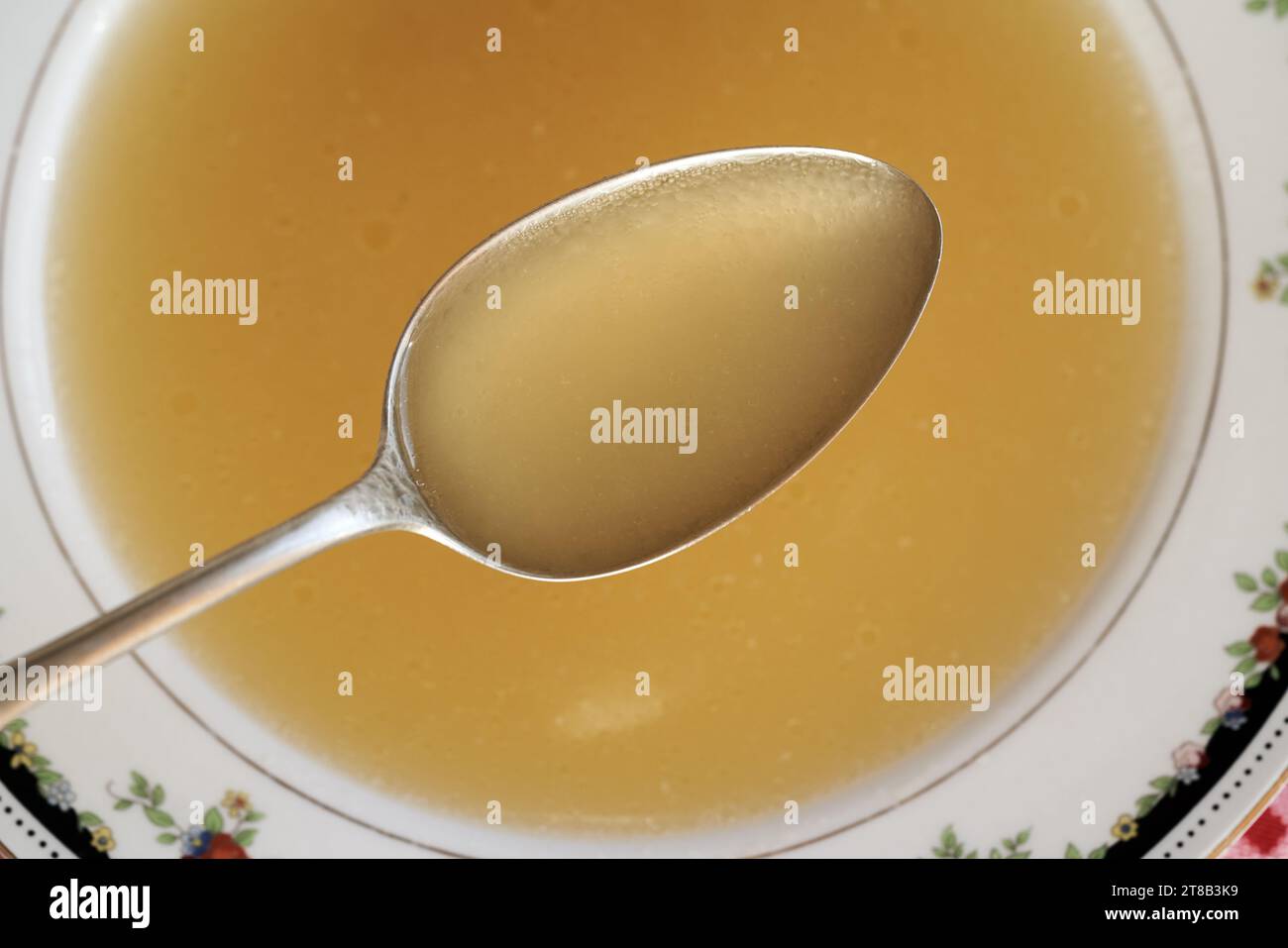 Chicken bone broth on a spoon above a soup bowl, top view Stock Photo ...