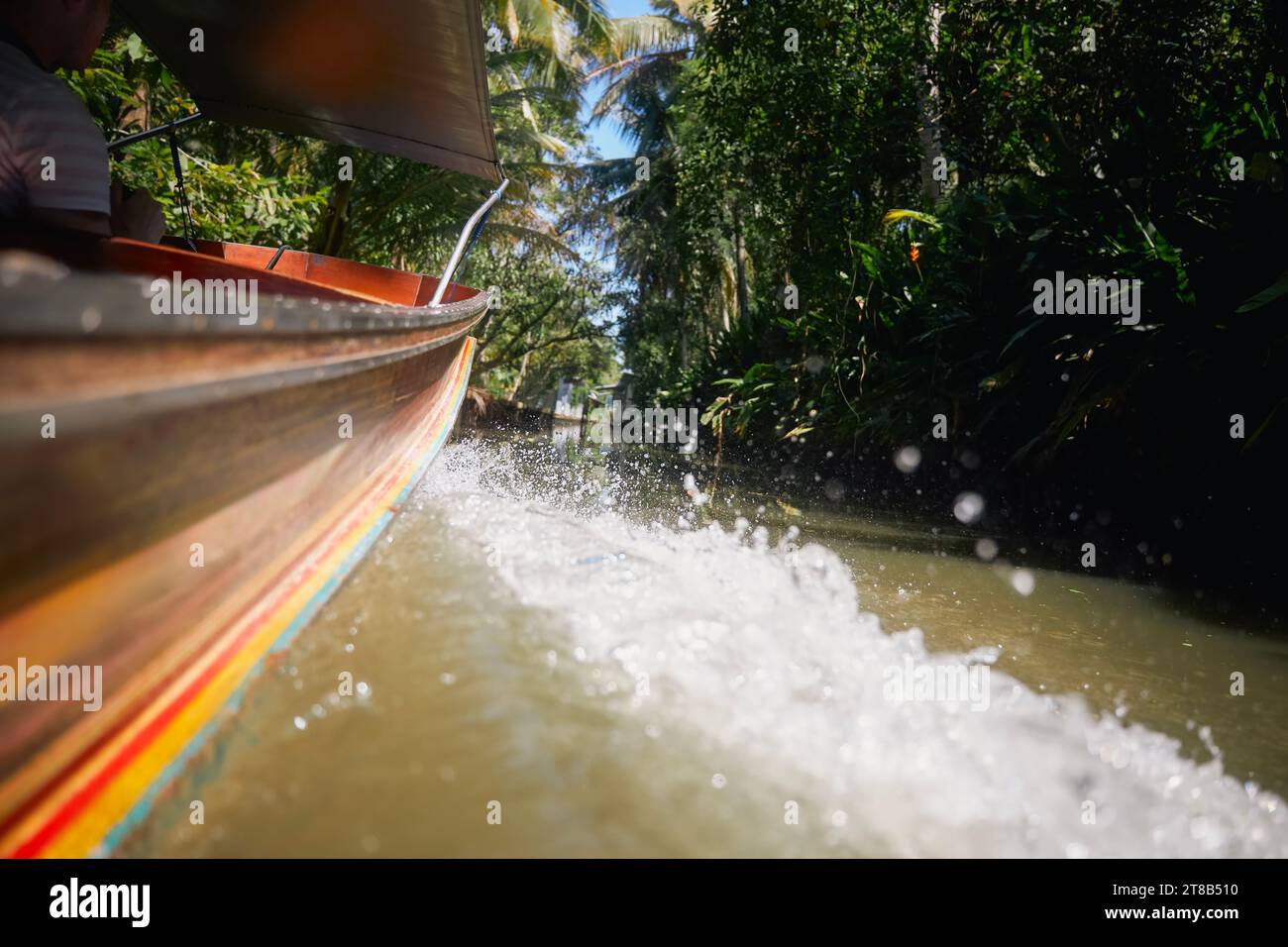 Rippled water and splashing drops behind traditional wooden long tail ...