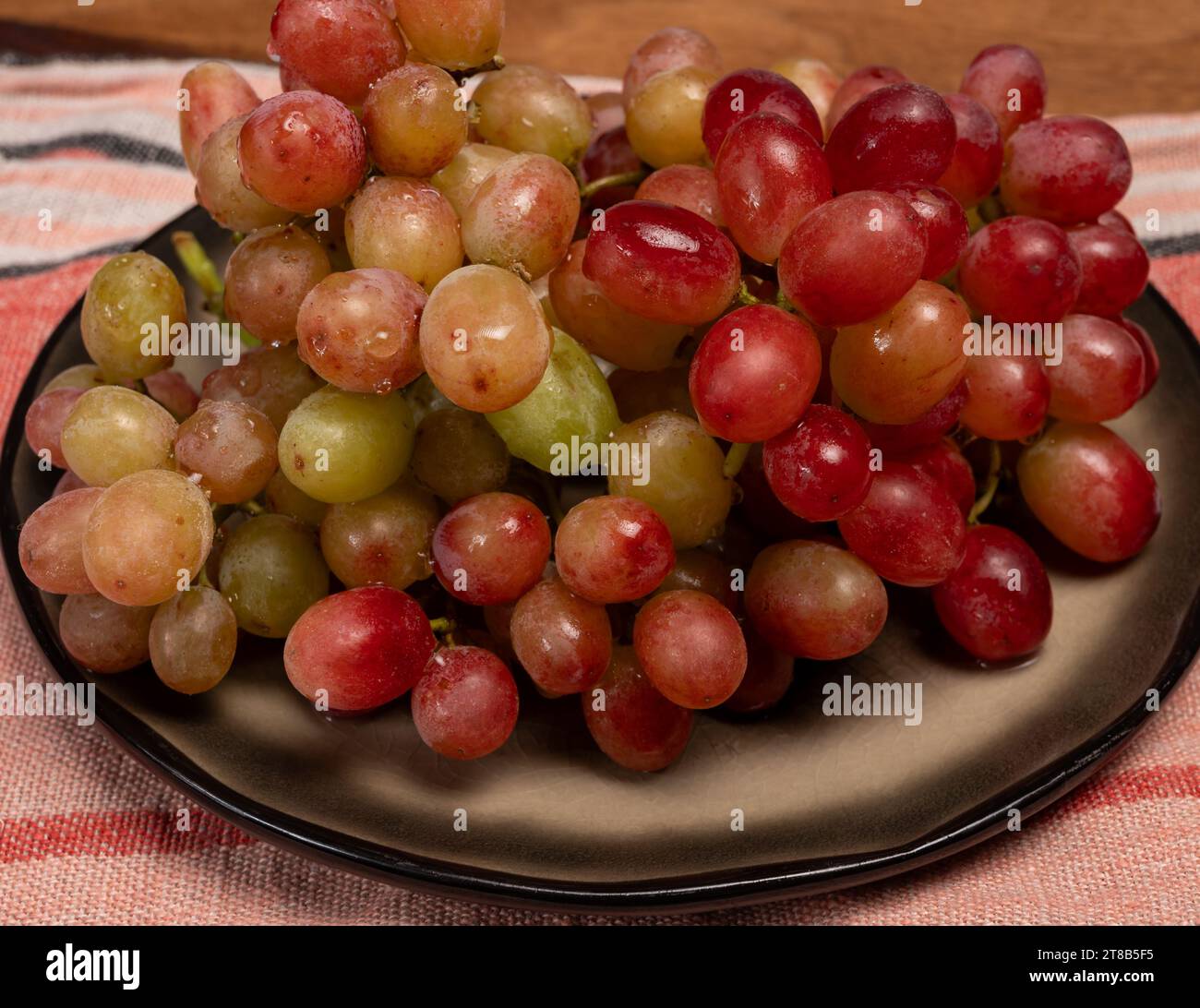 Sweet washed ripe pink grapes berries on board ready to eat close up ...