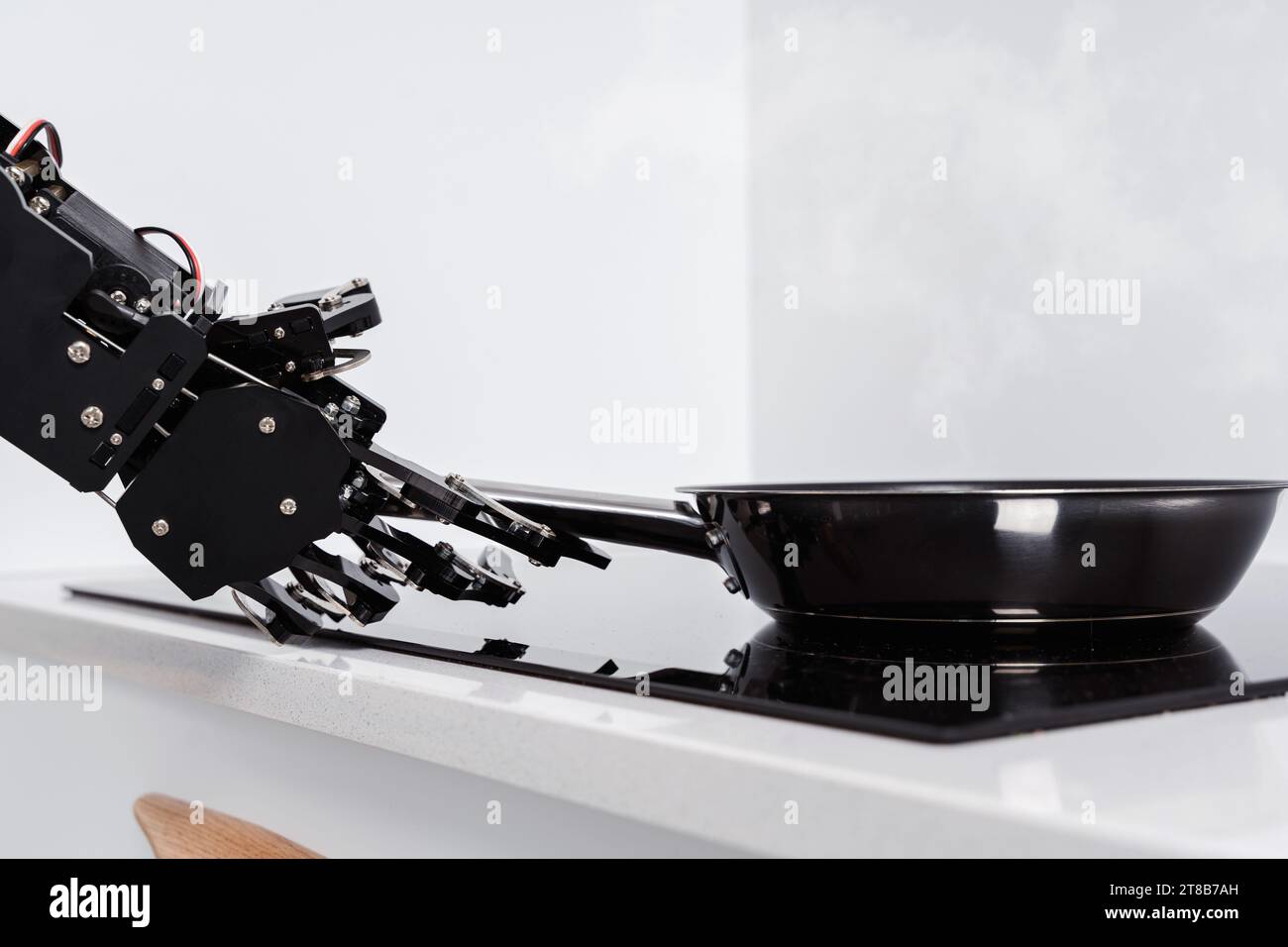 Real robot hand and frying pan on electric stove. Concept of robotic ...