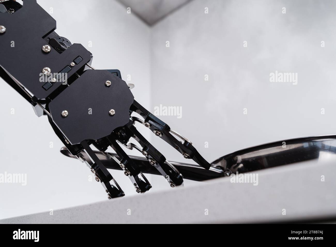 Real robot hand and frying pan on electric stove. Concept of robotic ...