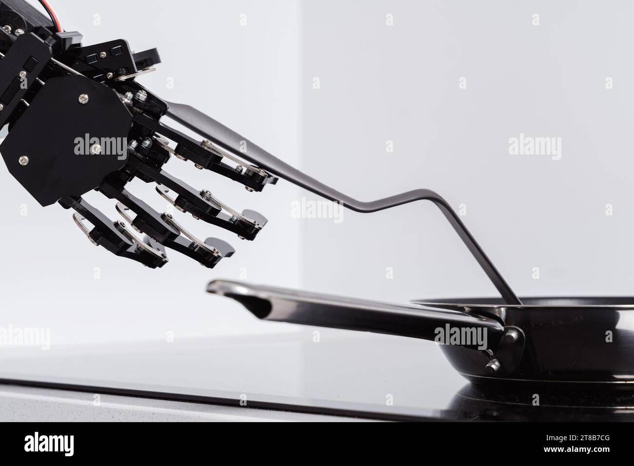 Real robot hand and frying pan on electric stove. Concept of robotic ...