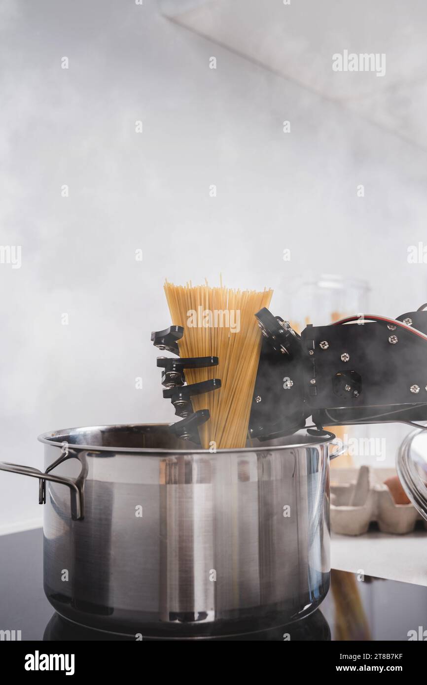 Real robot's hand add spaghetti into pot with boiling water. Concept of ...
