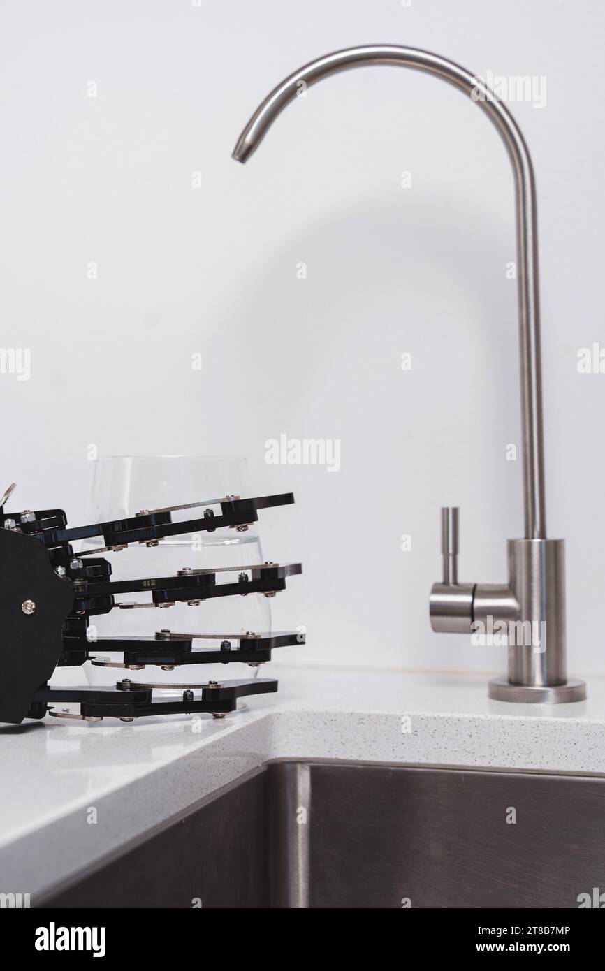 Real robotic hand get filtered water from stainless faucet into a glass ...