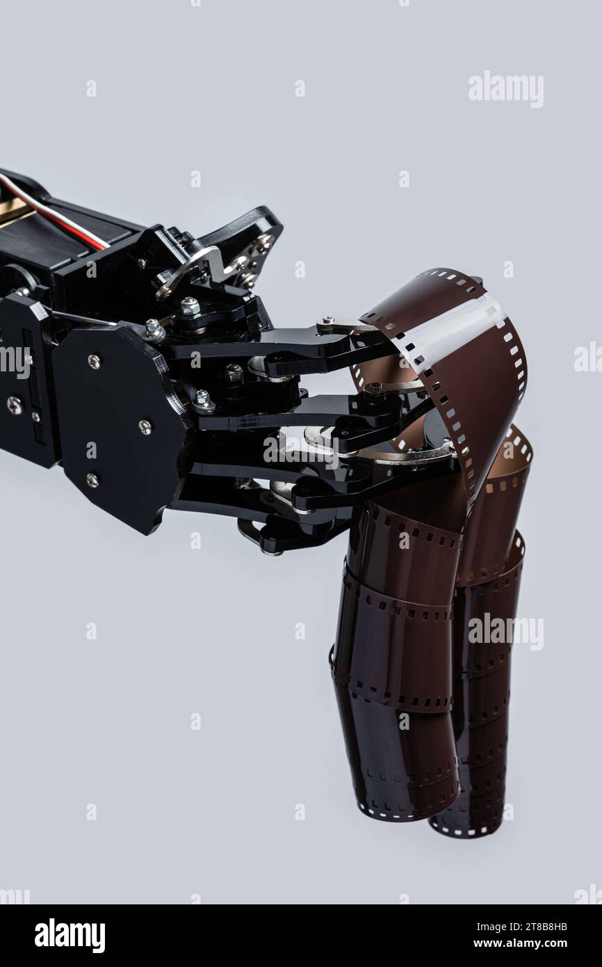 Real robotic hand with film stock. Concept of AI in motion picture and ...