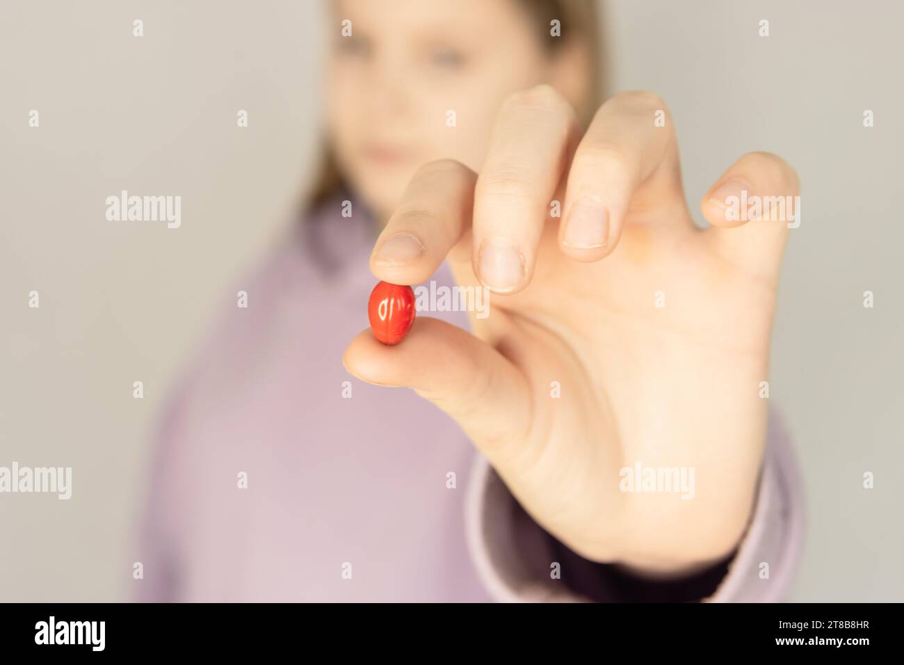 girl holding vitamin red in her hands close-up on a blurred background ...