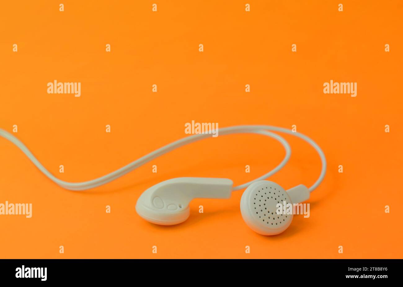 White modern headphones lie on a bright red background. A template for ...