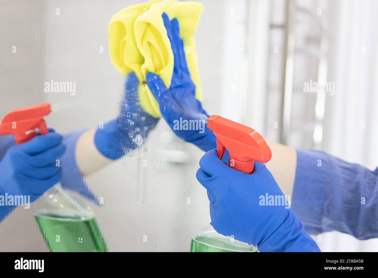 girl washing mirror with yellow cloth in blue gloves at home.House ...