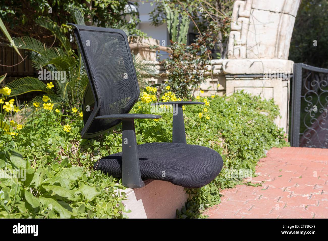 an old chair on the street in a provincial town stands on green grass ...