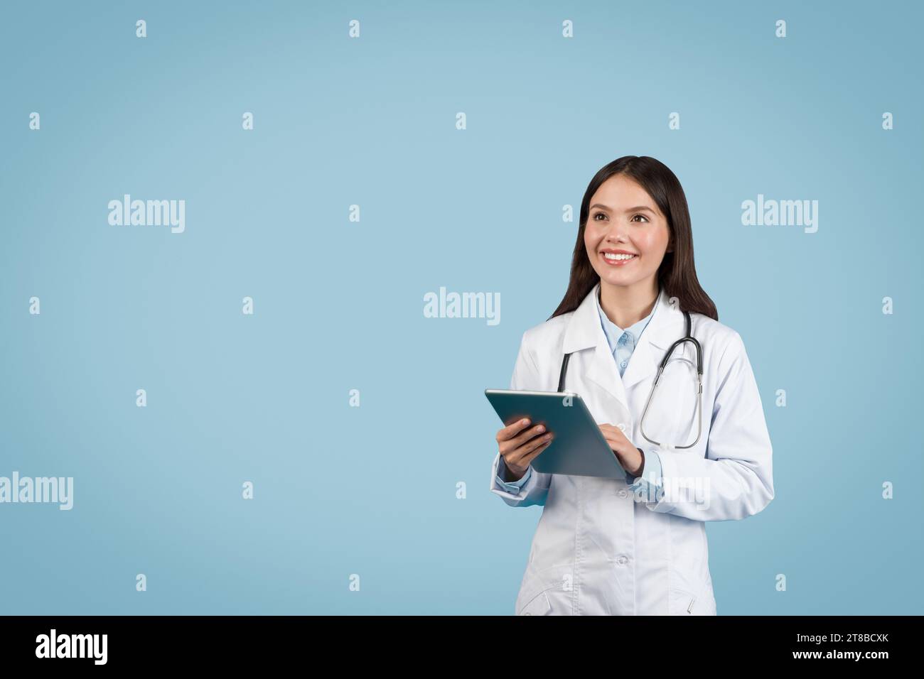 Cheerful female doc in white coat with digital tablet looking at free ...