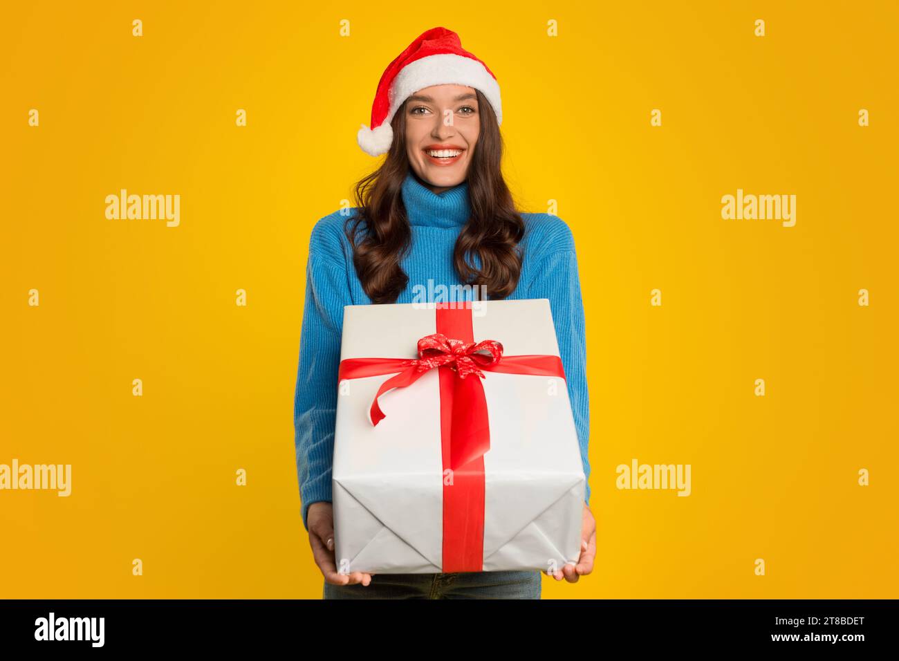 Happy woman poses with wrapped gift box on yellow background Stock ...
