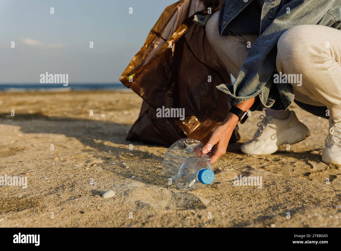 Woman volunteer is collecting plastic waste on the beach to contribute ...