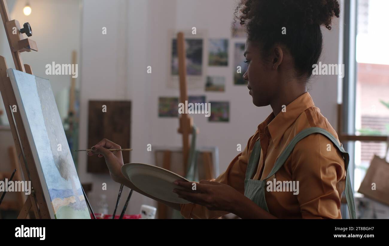 Young African American stylish female pretty artist painting ...