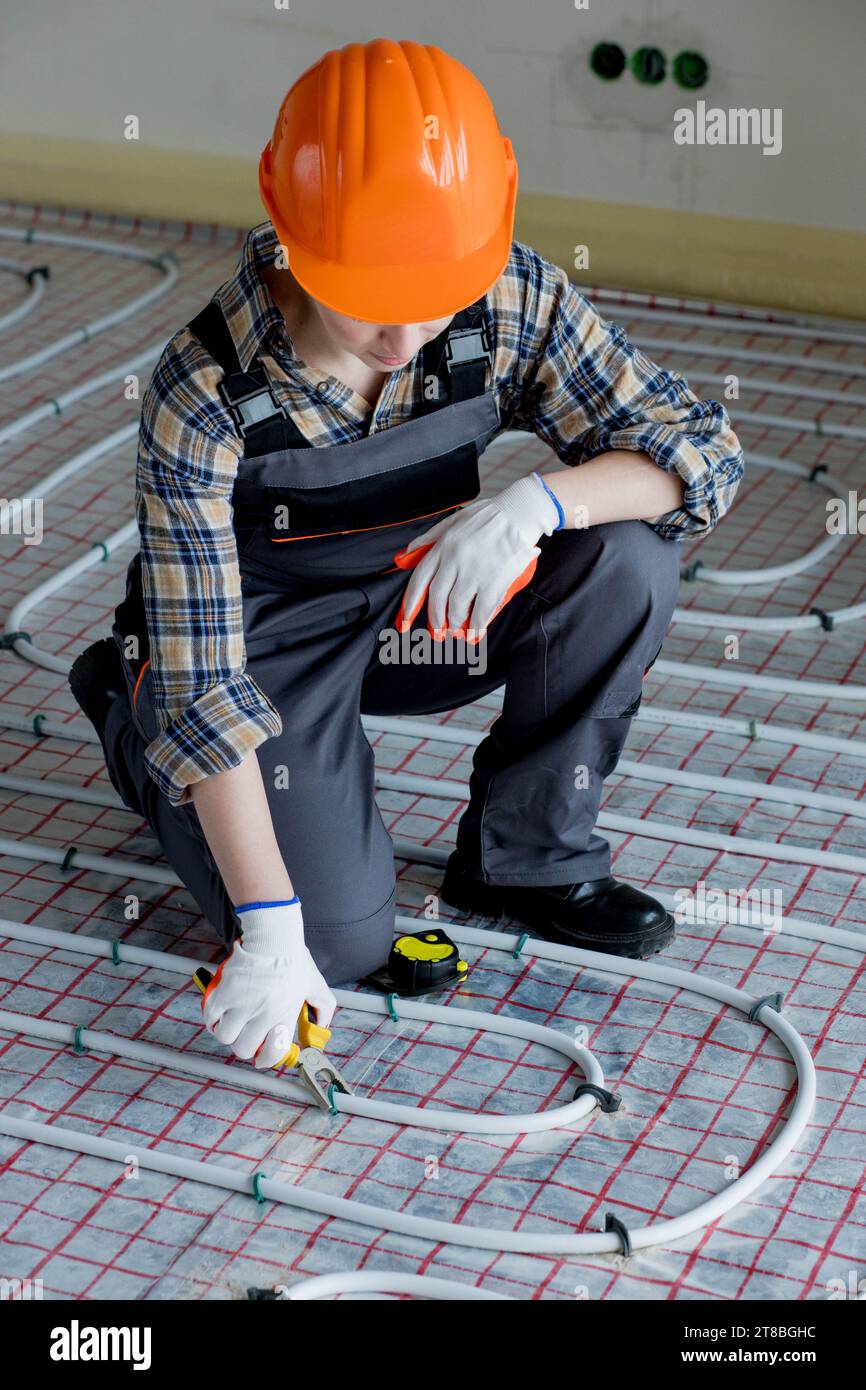 Woman worker is installing underfloor heating system. Warm floor ...