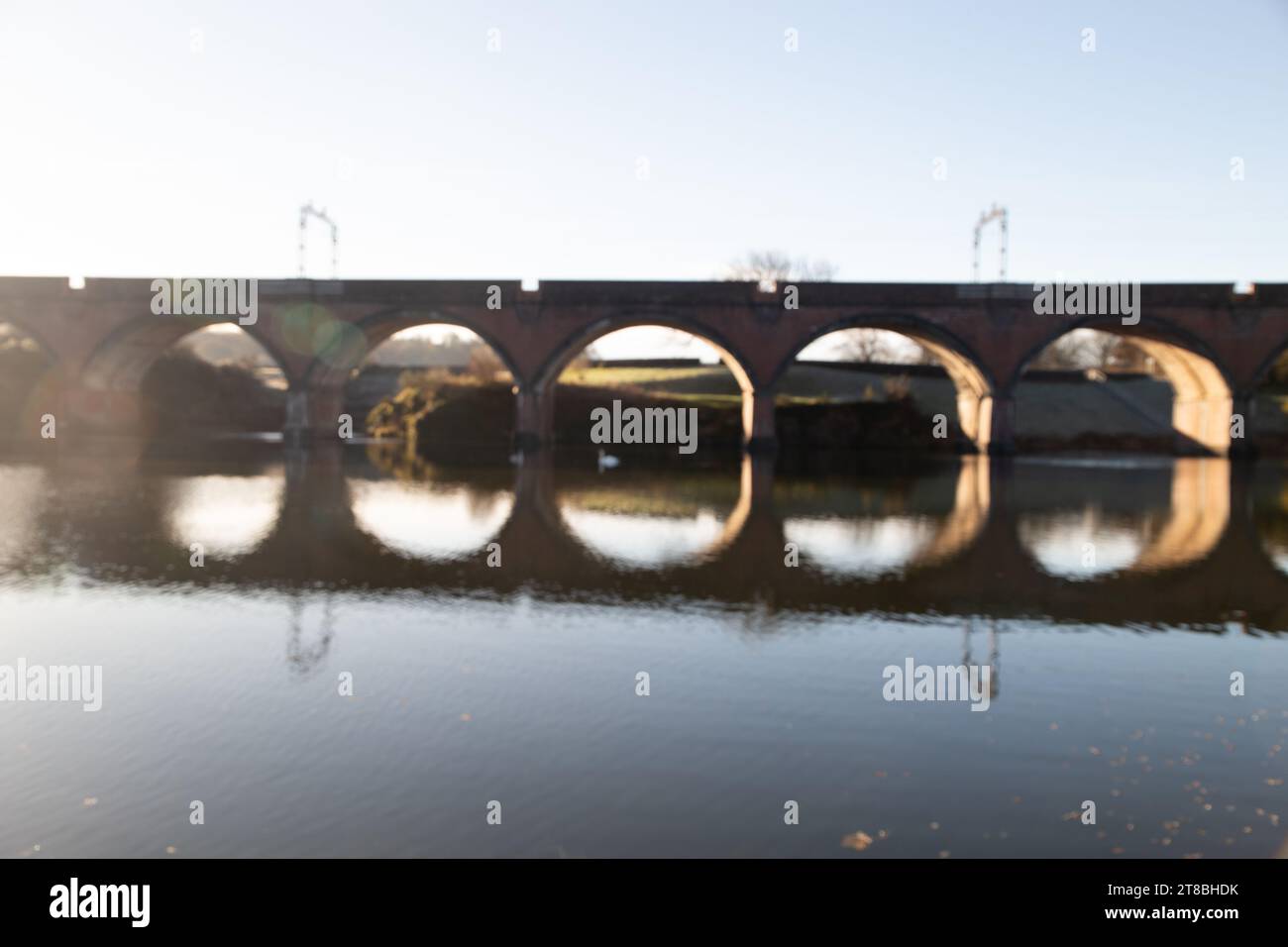 A railway bridge over a reservoir in Scotland on a clear winters ...