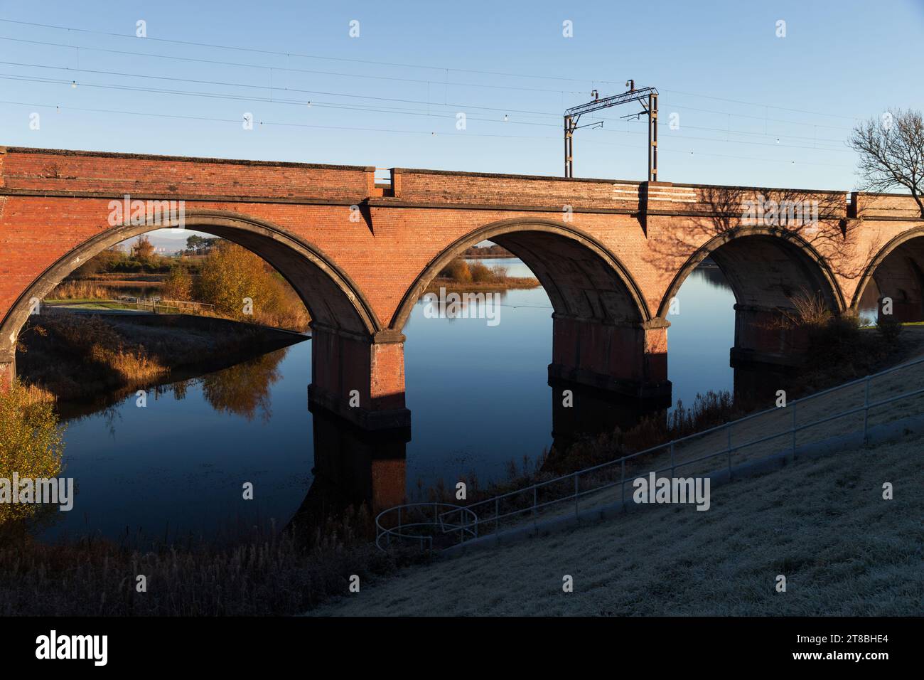 A railway bridge over a reservoir in Scotland on a clear winters ...