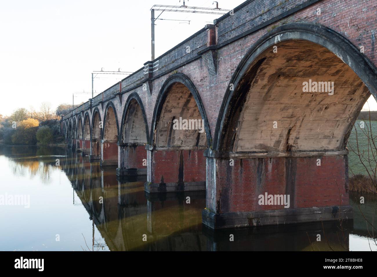 A railway bridge over a reservoir in Scotland on a clear winters ...
