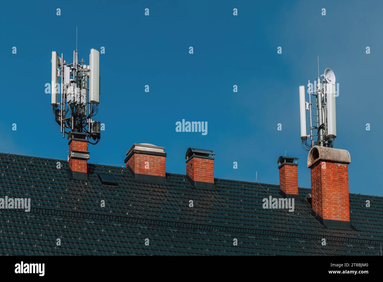 Mobile telephony base station and signal repeater antenna on building roof, telecommunication ...