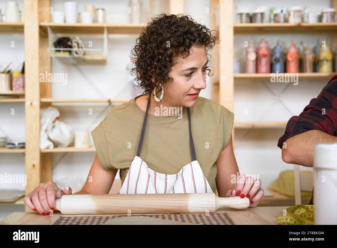Woman with a rolling pin looking at her partner while making crafts in ...