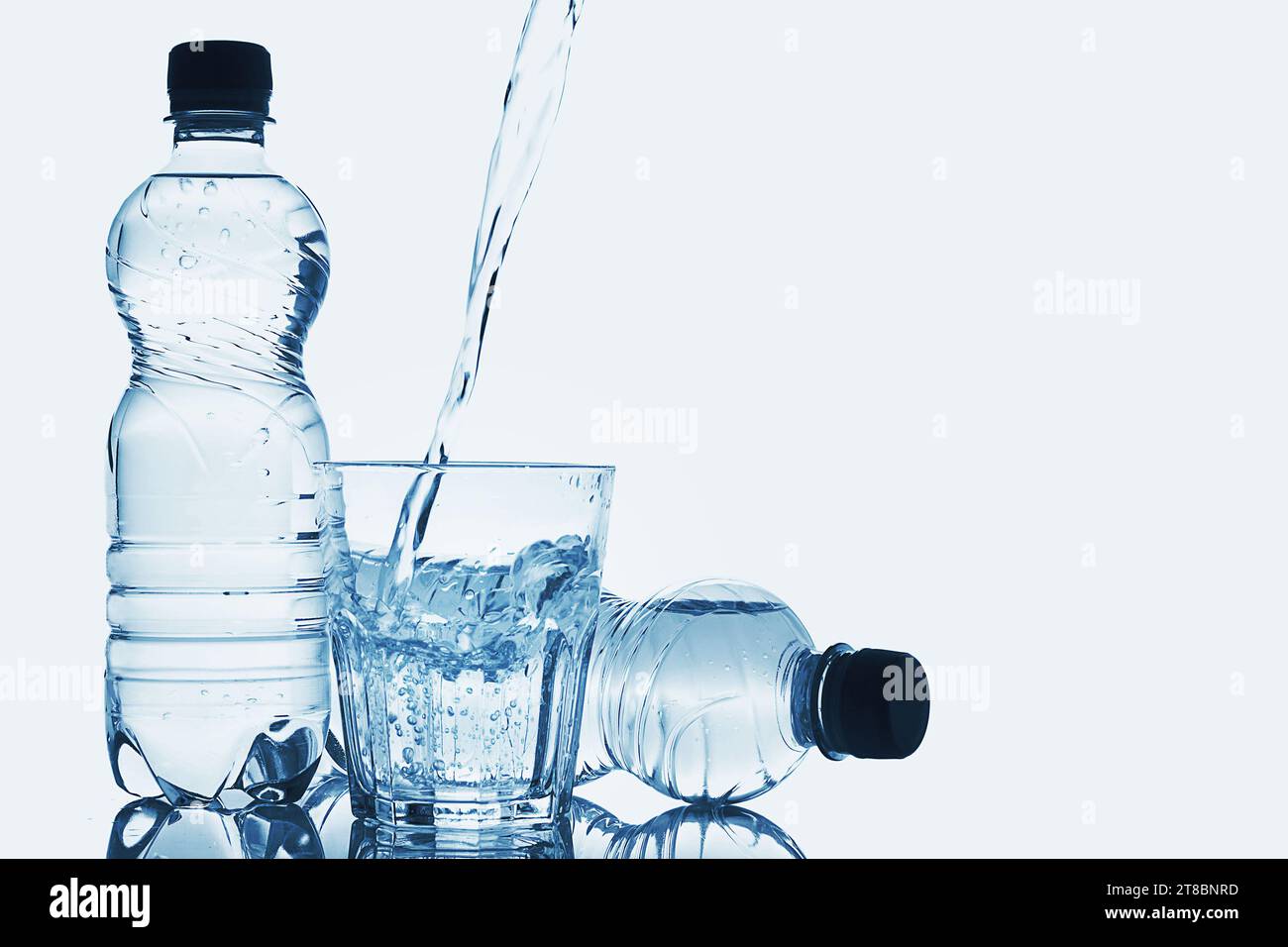 Blue bottles and pouring of pure still water into glass on white background Stock Photo - Alamy