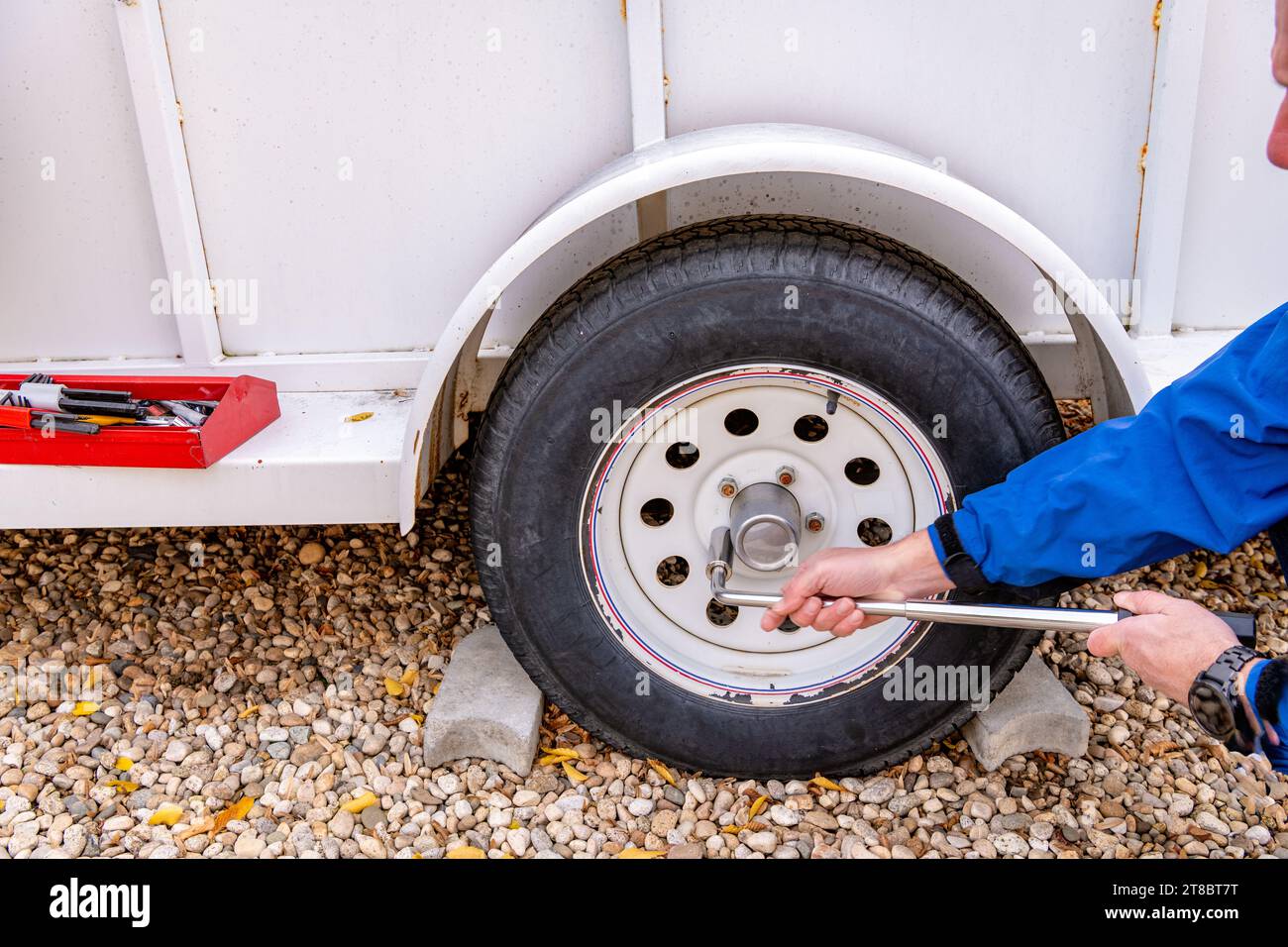 Homeowner works to remove a wheel from a utility trailer Stock Photo ...