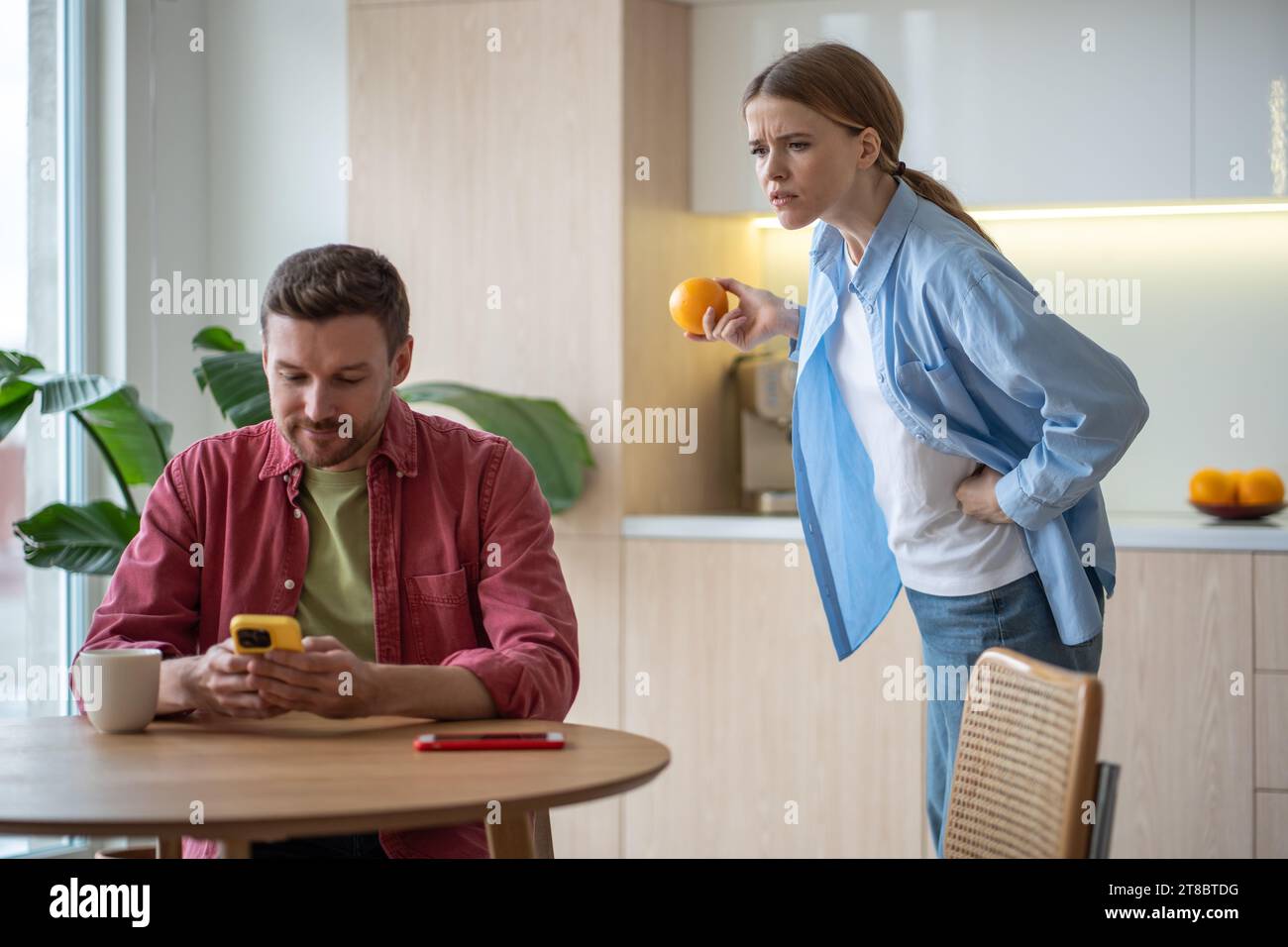 Frowning woman peeks into smartphone of grinning man, suspecting of ...