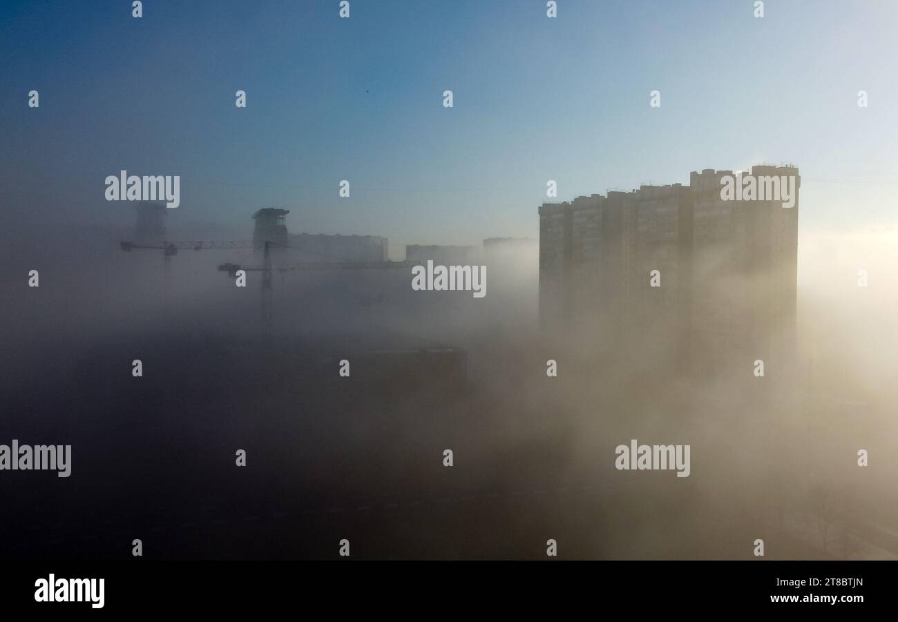 Construction cranes and a multi-storey residential building, shrouded ...