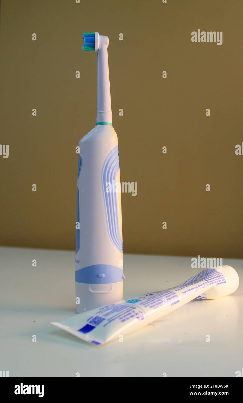 A photo of a tall, white electric toothbrush beside a squeezed tube of ...