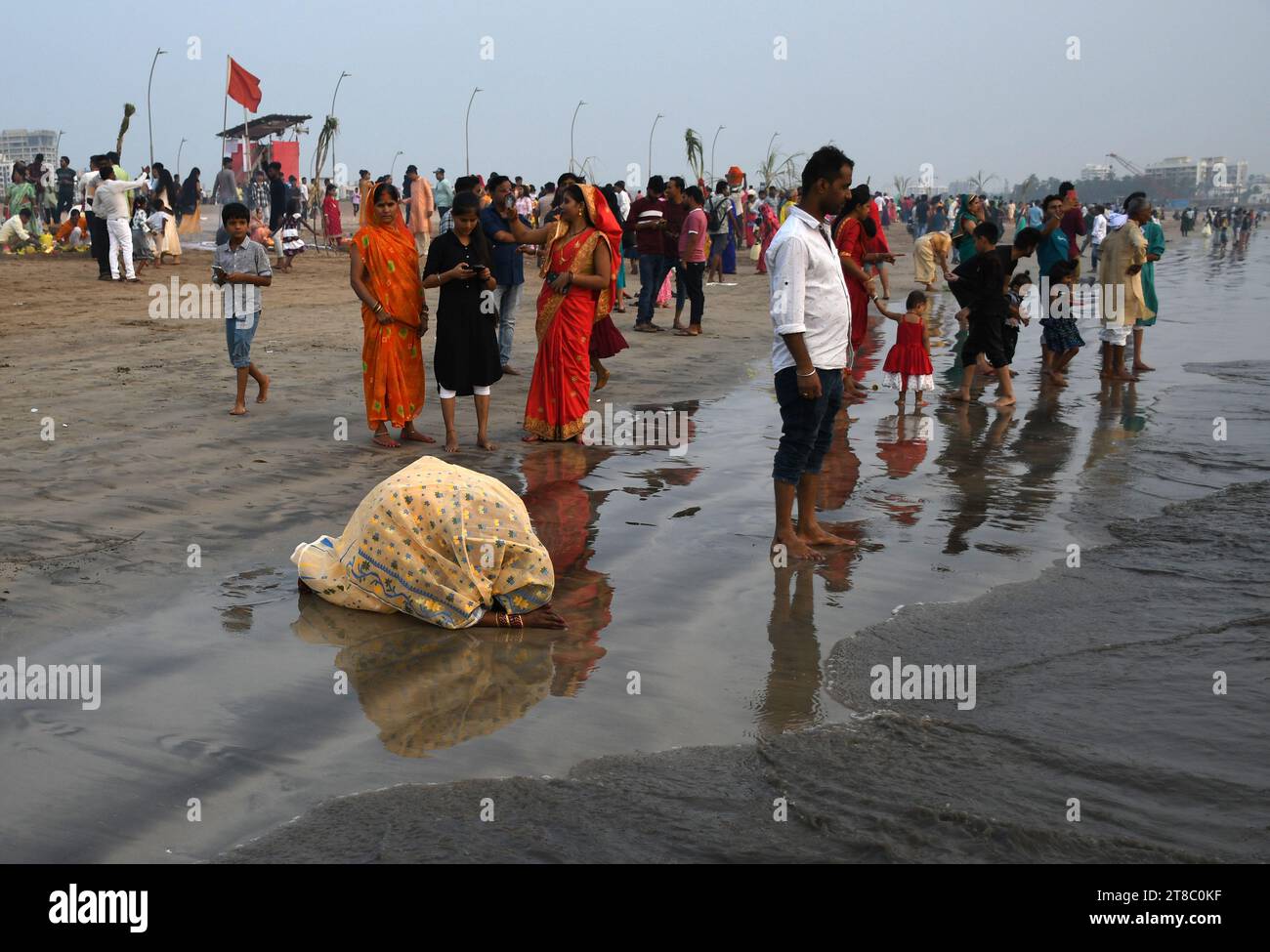 A Hindu woman (left) bows to the setting sun (not in picture) on the ...
