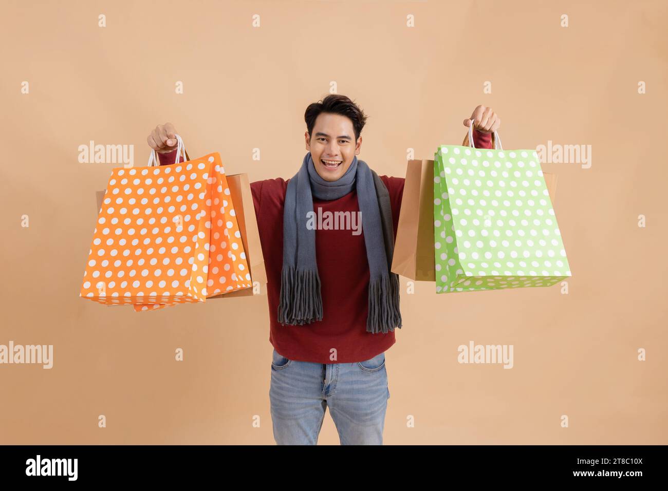 Happy smiling Asian male shopper holding a bunch of shopping bags while ...
