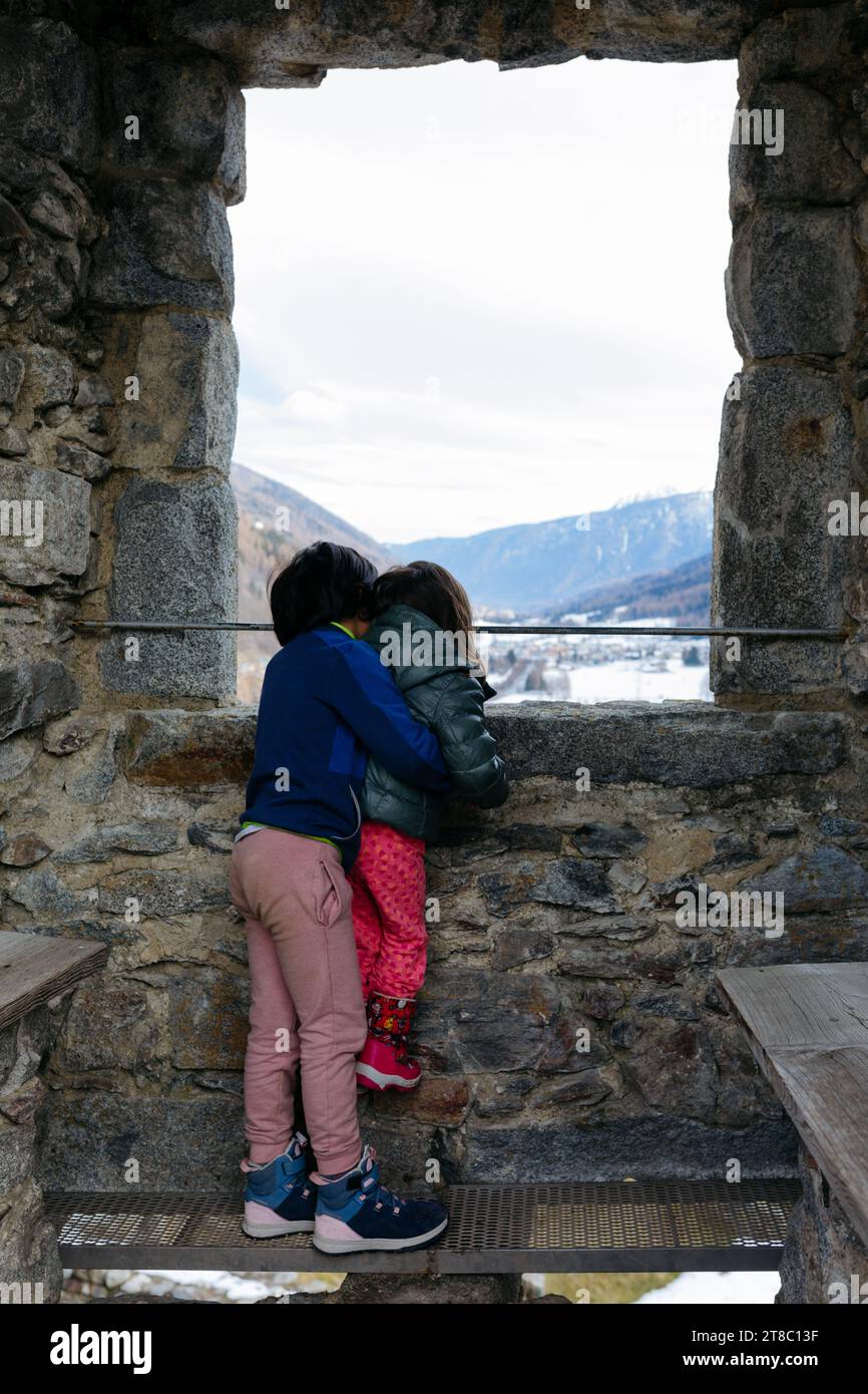 bigger child holds smaller child in arms helping to see from the window ...