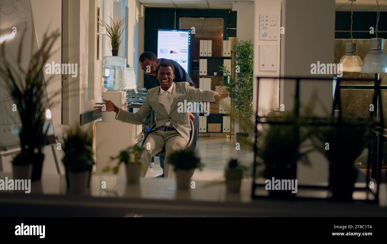 Playful worker jesting with unattentive colleague, pushing his desk ...