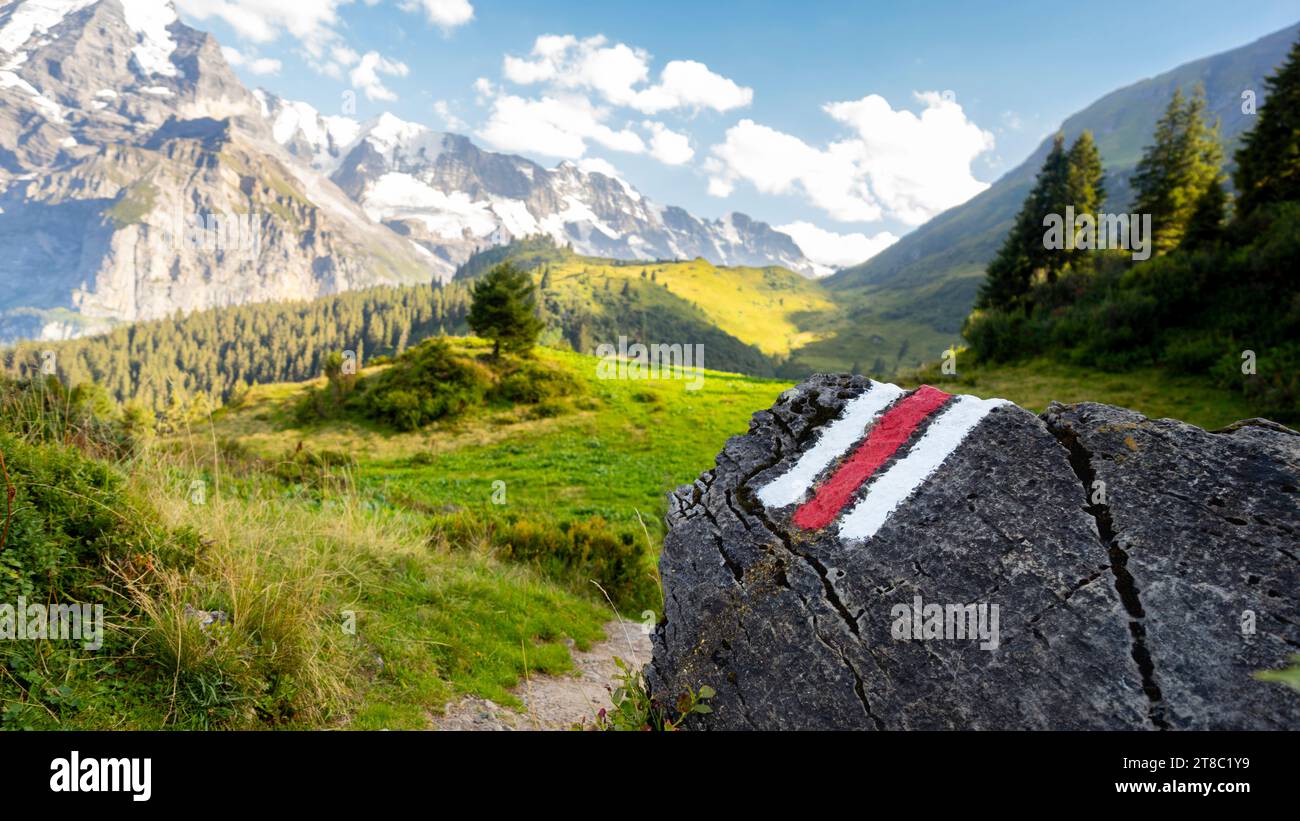 White and red trail waymark in a hiking path in the Swiss Alps with ...