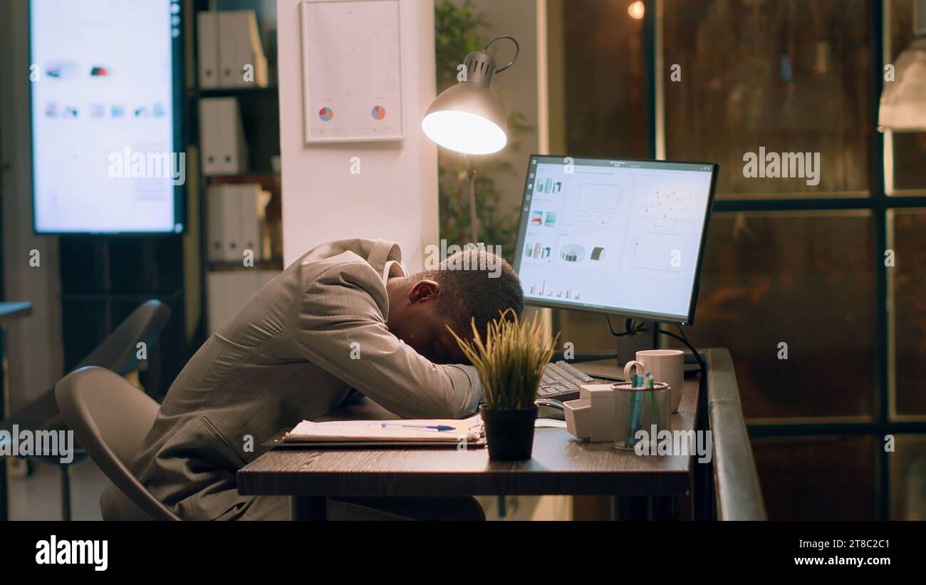 Overworked african american businessman asleep in desk chair while ...